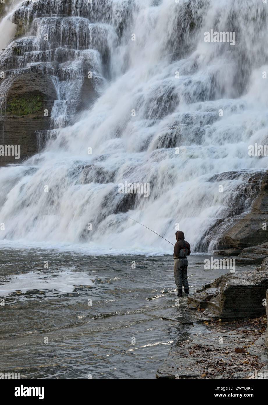 man with fishing rod in creek (shot from behind, no face ...