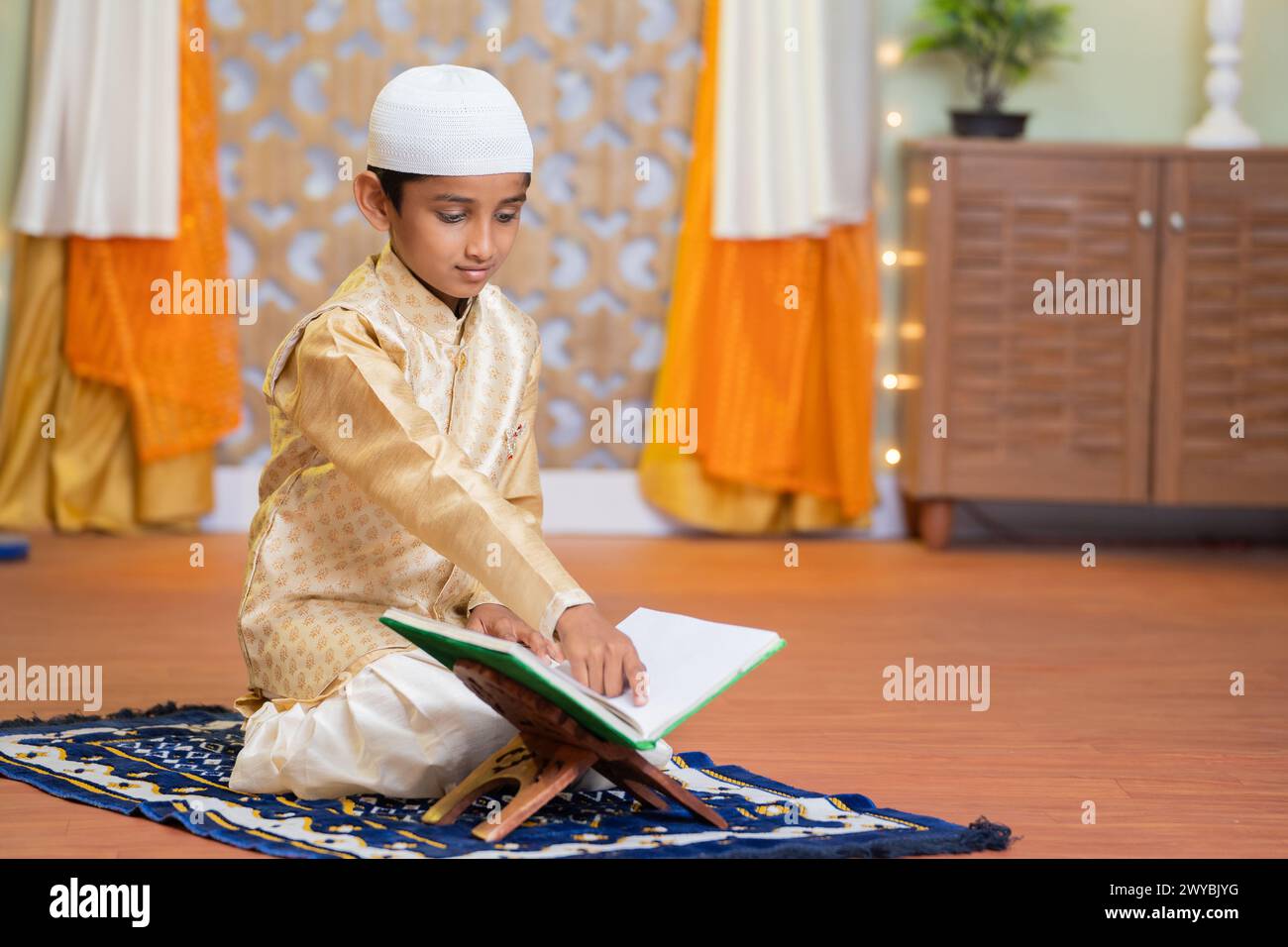 Young teenagaer muslim boy reading Quran book during Ramadan feast ...