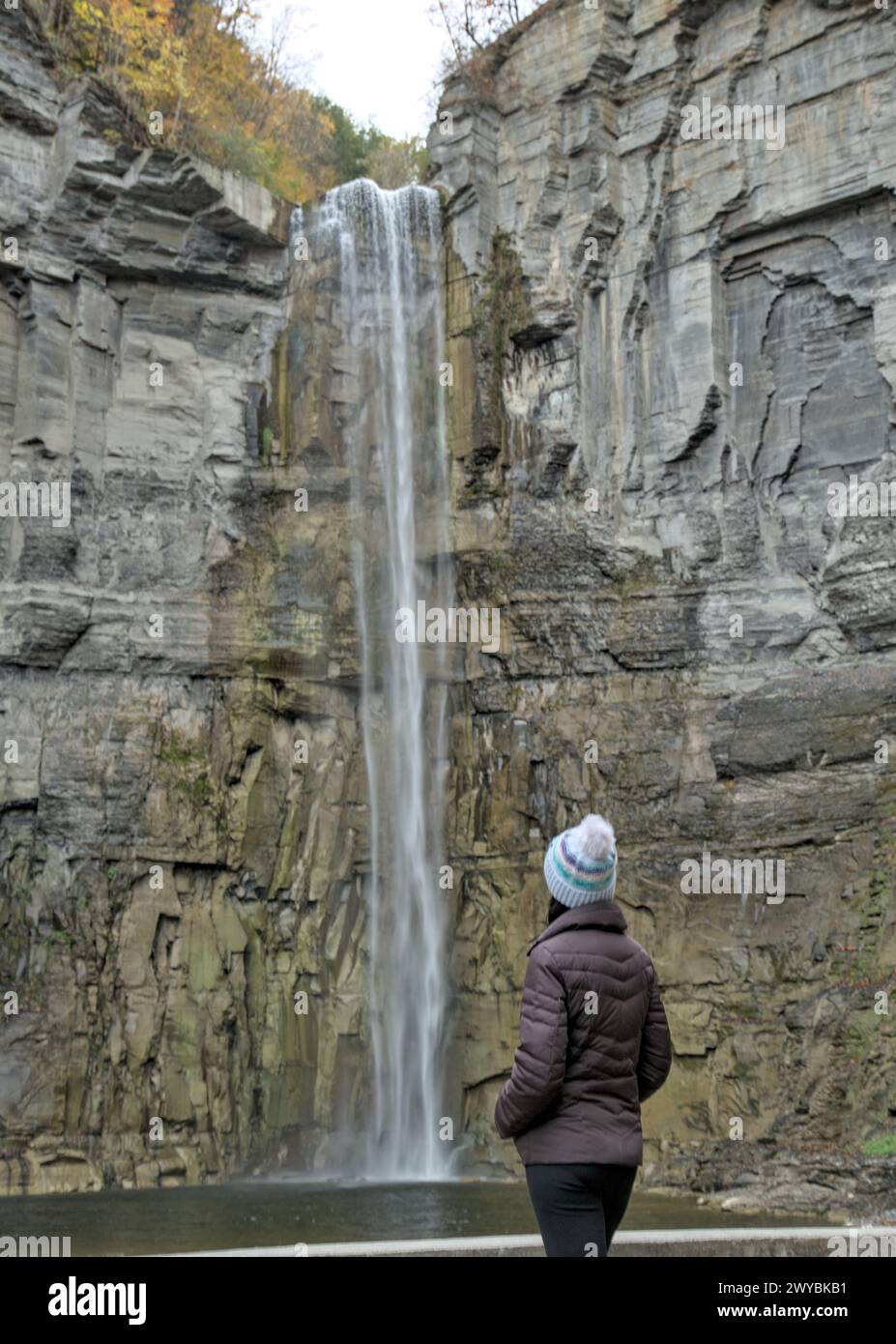 woman looking at a waterfall on a nature hike (photographed from behind ...