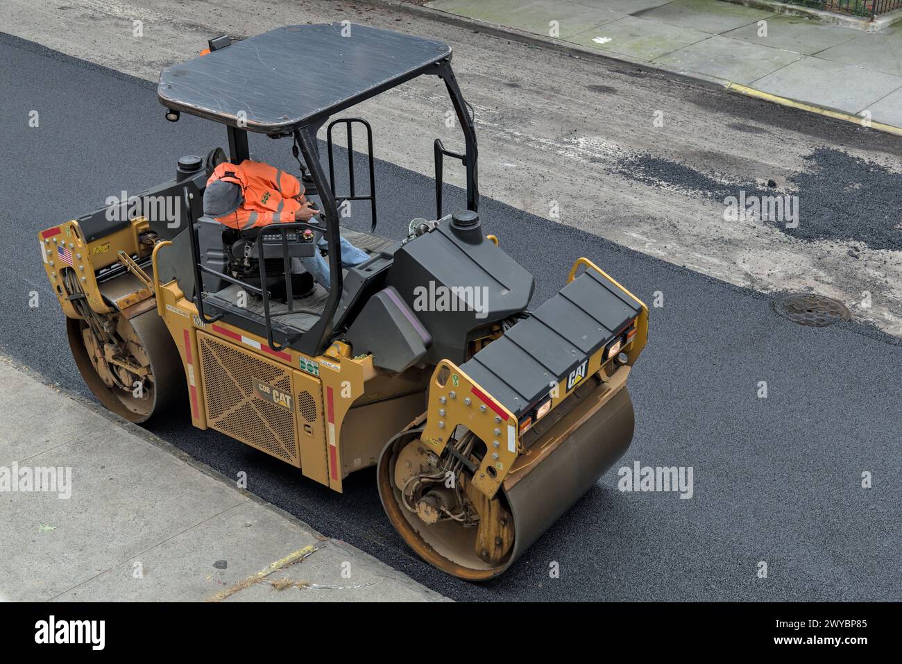 city worker paves road with paving vehicle (new asphalt installation on ...