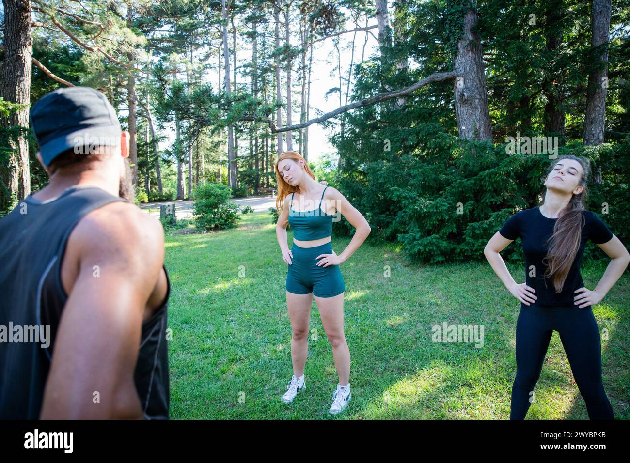 Three people are exercising in a park, personal trainer is holding a ...