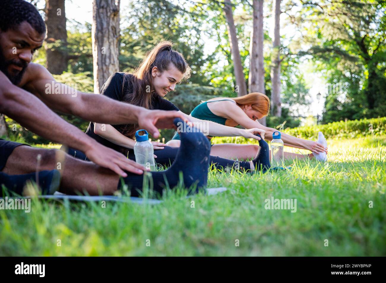 Close up of the feet of three sporty people who are stretching in a ...