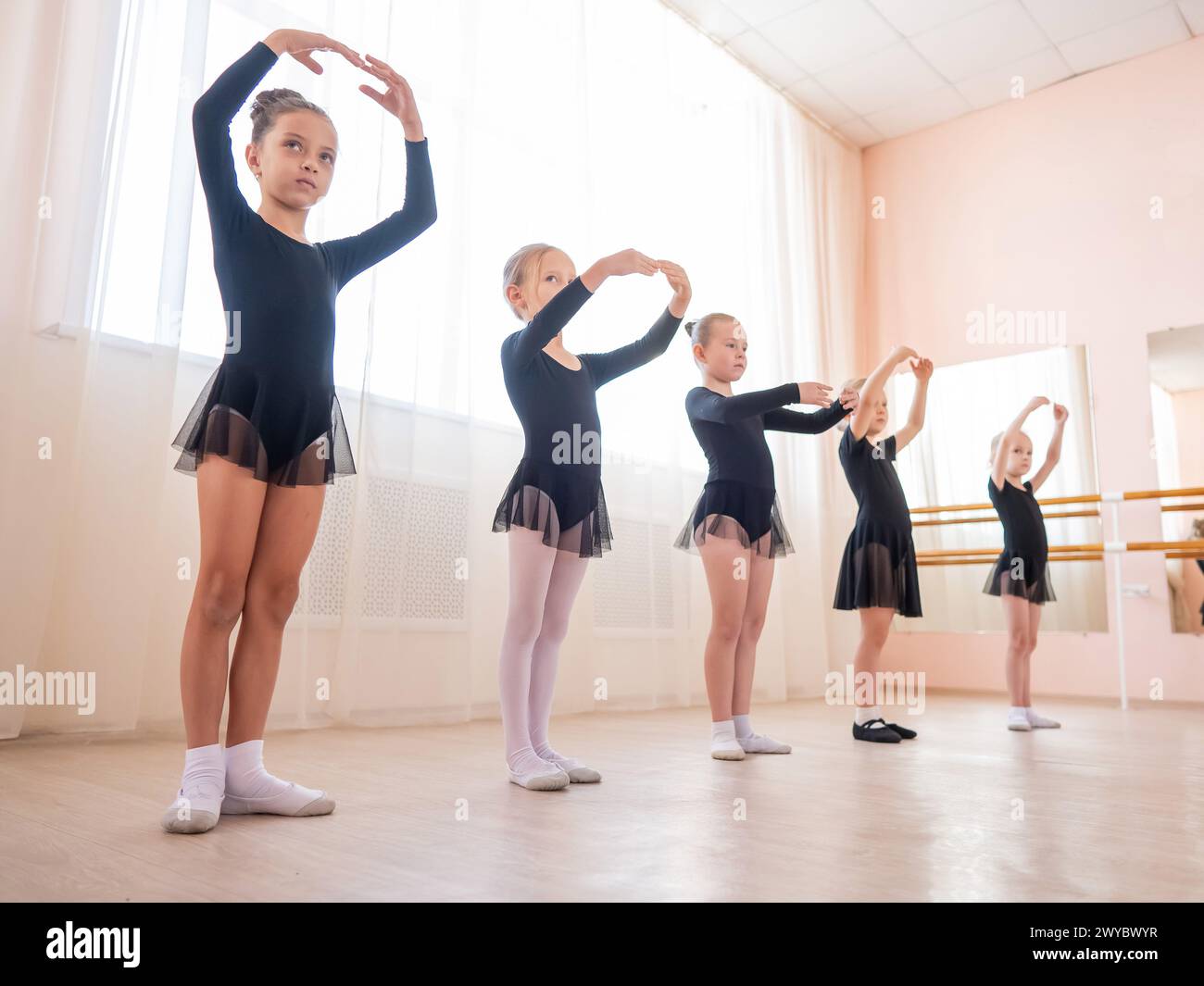 Cute little girls in black swimsuits and tutu practice ballet in class ...