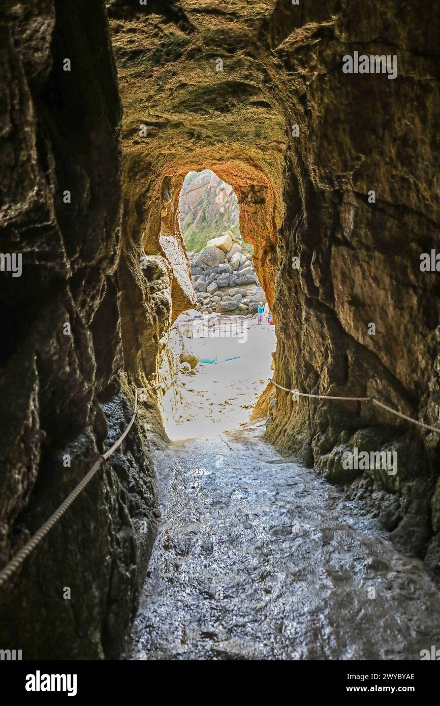 A gap in the rocks or a rock arch or tunnel at Porthgwarra, Cornwall ...