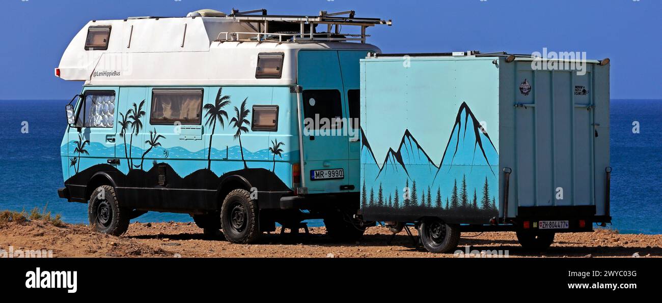 Colourfully painted camper van and matching trailer looking out across ...