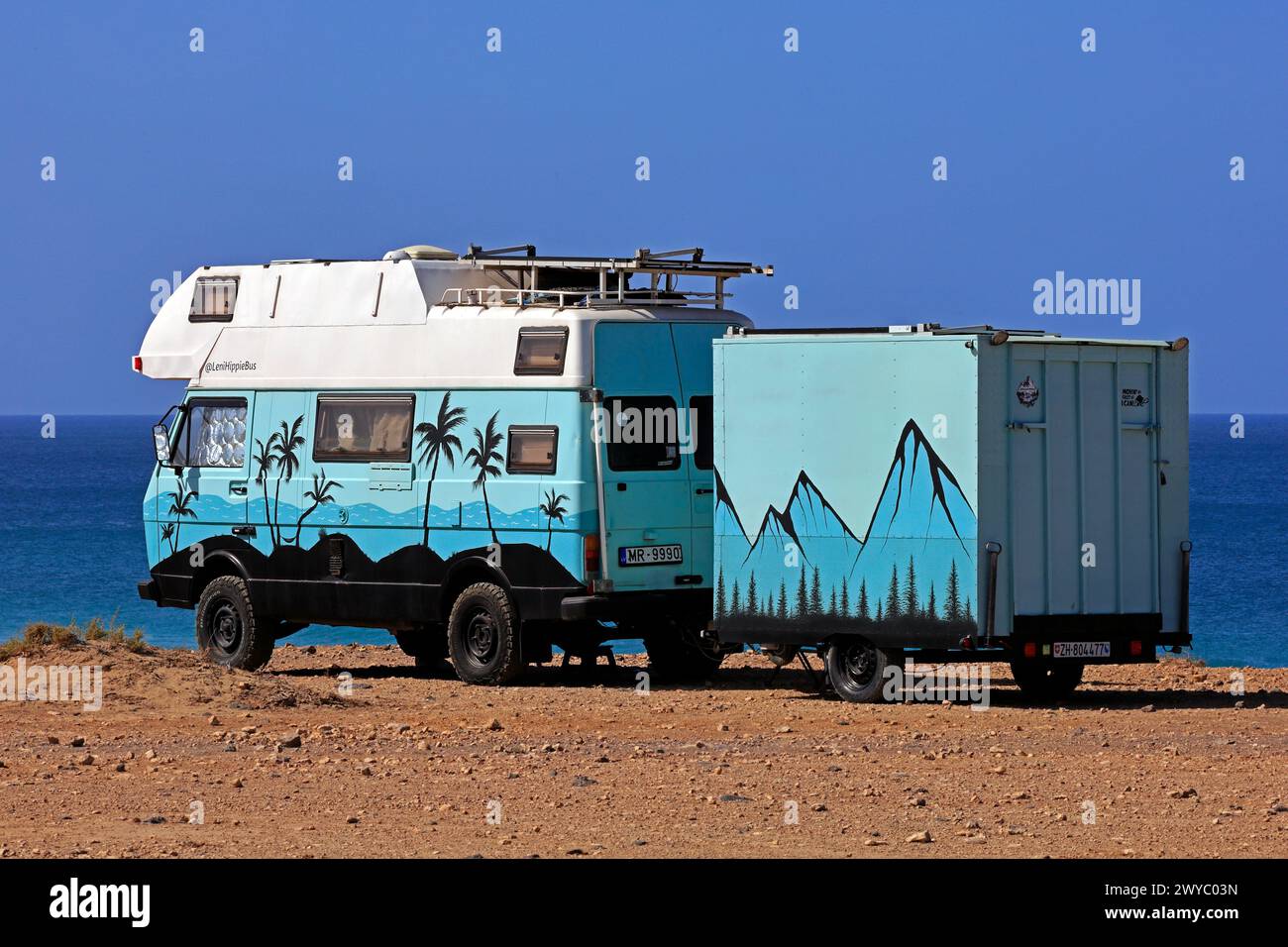 Colourfully painted camper van and matching trailer looking out across ...