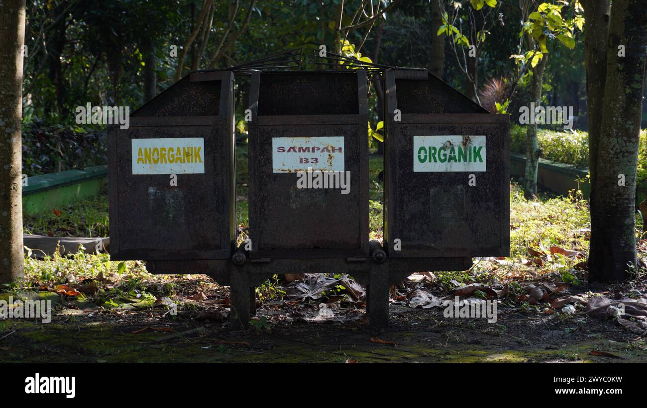A rusty trash can in a park separated into three categories of waste ...