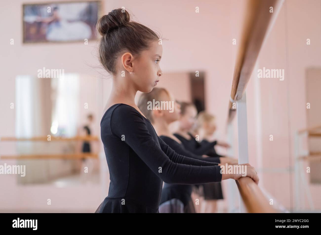 Cute little girls in black swimsuits and tutu do ballet at the barre ...