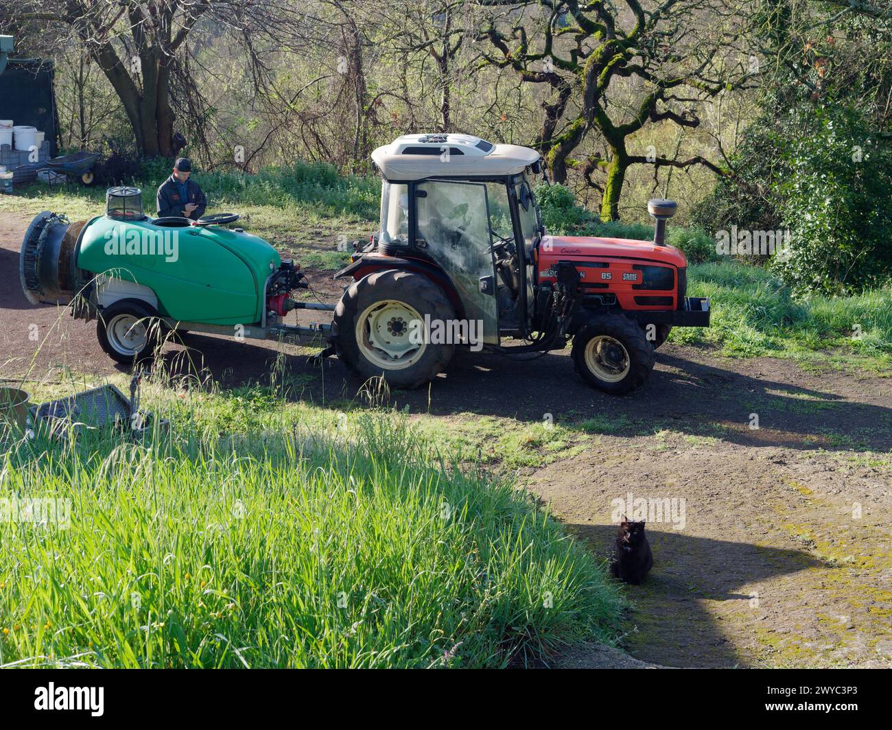 Tractor with treatment sprayer device with farmer and cat in ...
