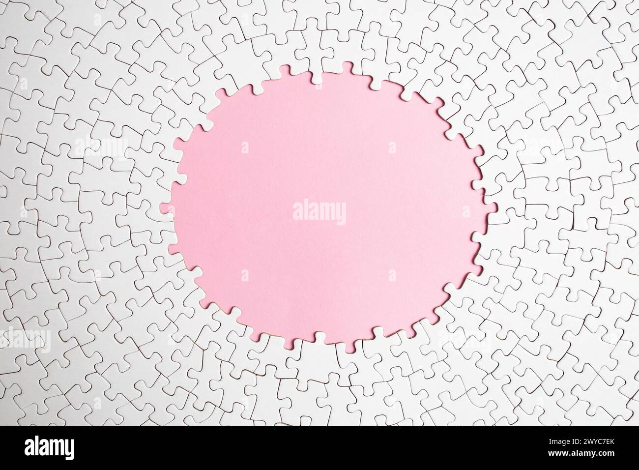 Plain white jigsaw puzzle on pink color background, oval shaped frame ...