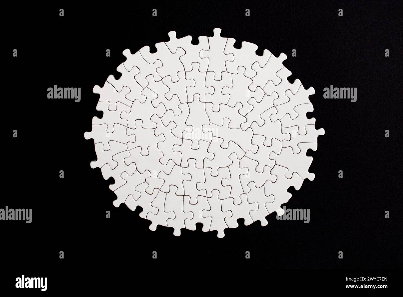 Plain white jigsaw puzzle on black color background, oval shaped frame ...