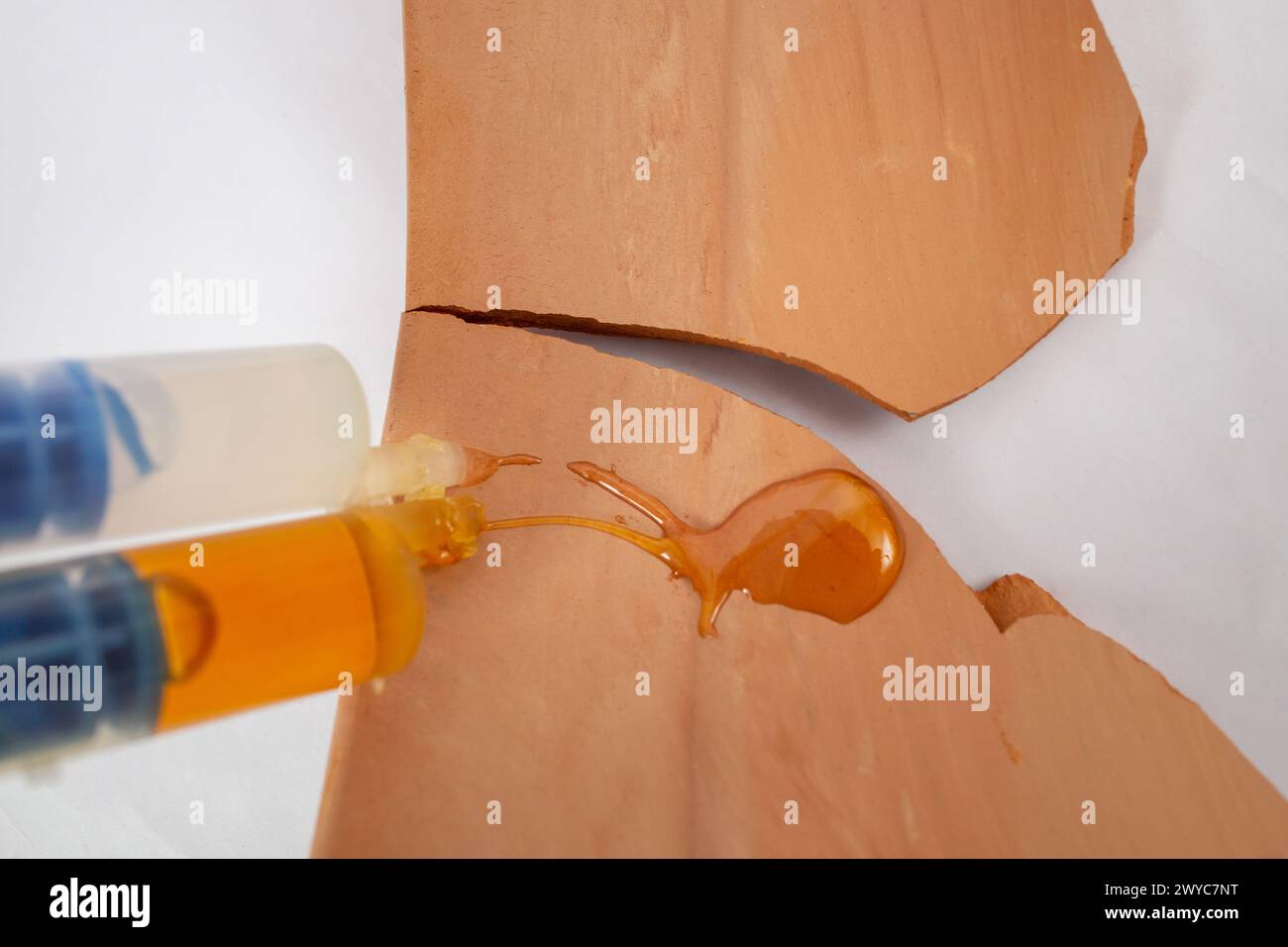 Double syringe with epoxy gel gluing and spilling on broken brown ...