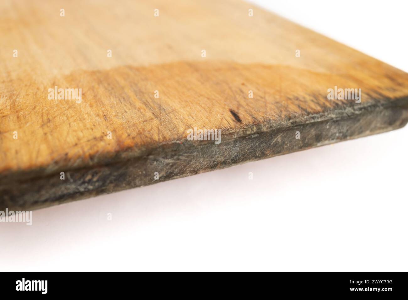 Wooden chopping board with cut marks and black mold, close up on white ...