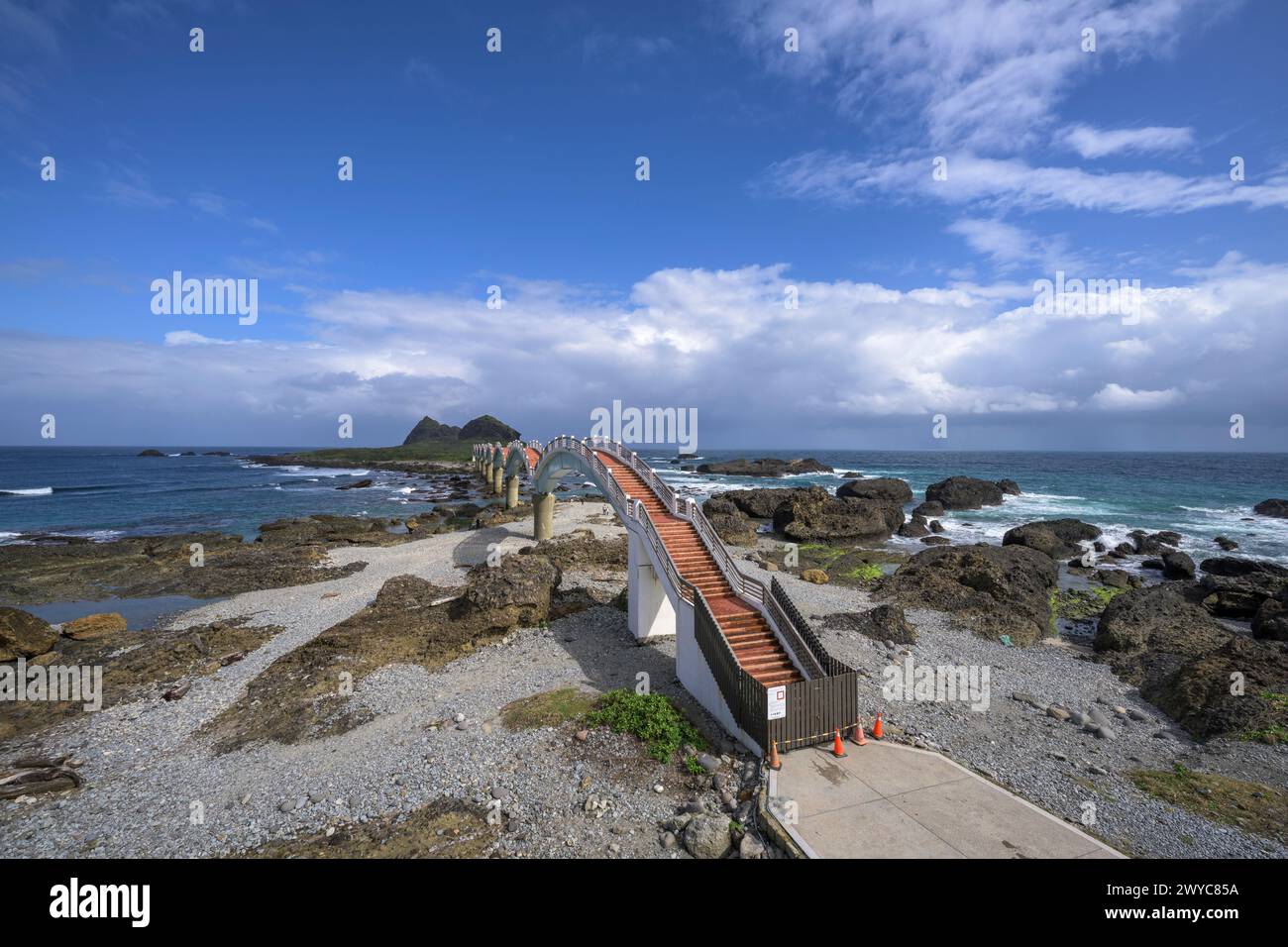 A stunning Sanxiantai Arch Bridge spans across a rocky coastal scene ...