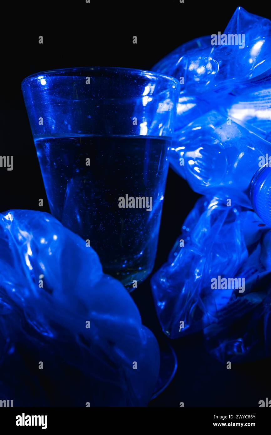 A Mazagran glass, with tap water and compressed plastic bottles, on a ...