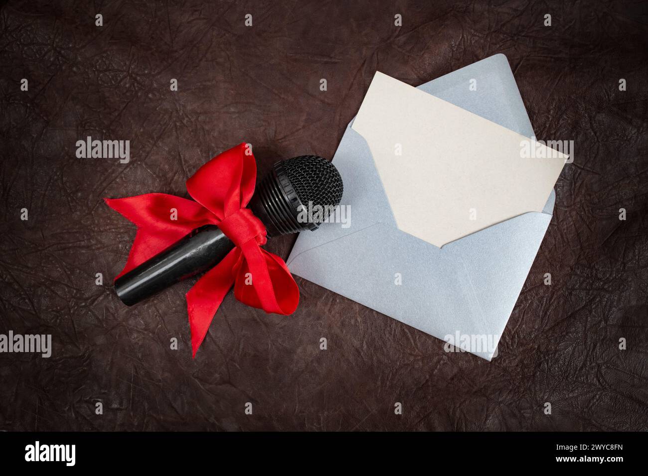 microphone with a red ribbon bow next to a silver envelope and a blank ...