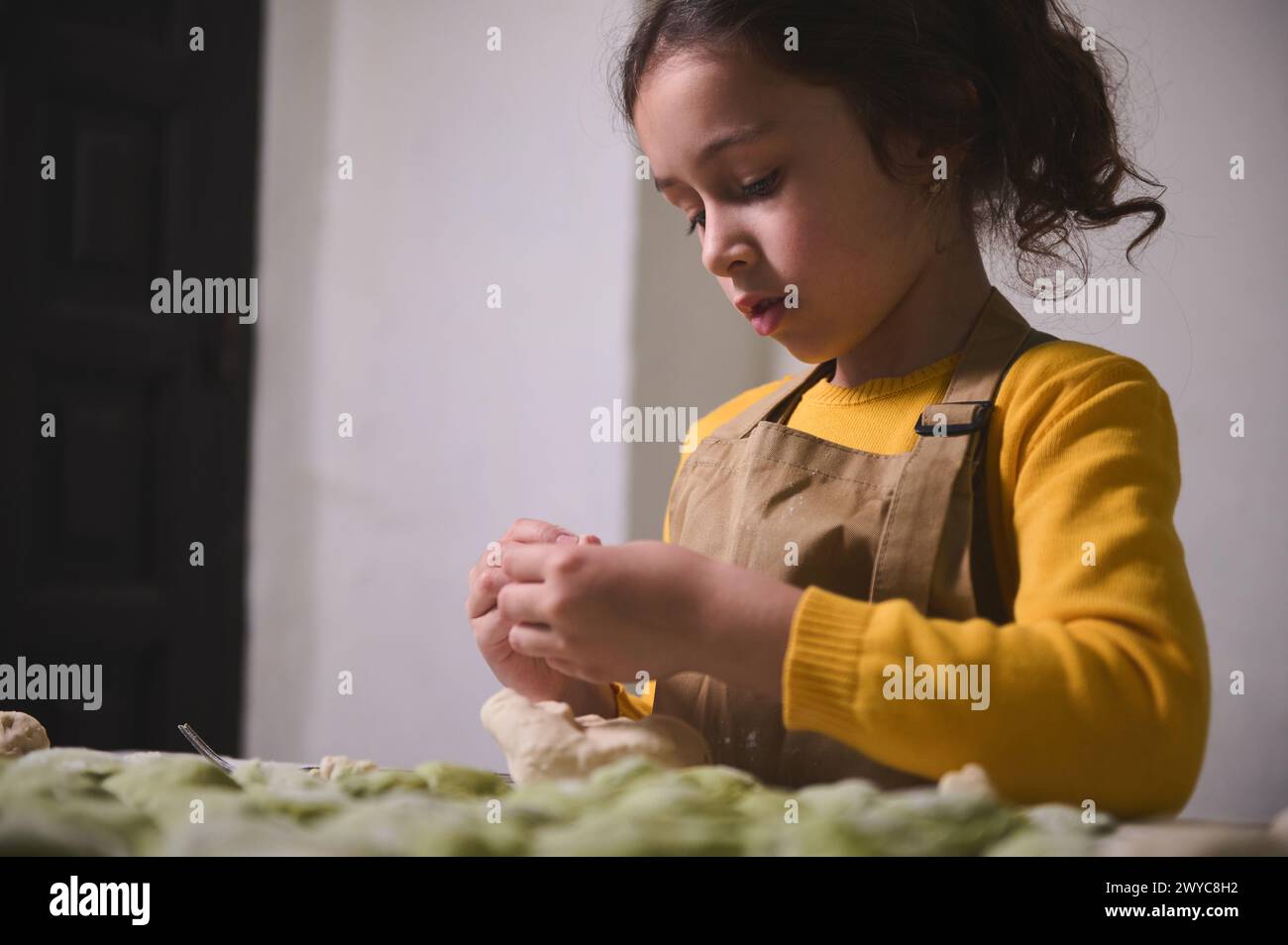 Little girl stuffing and molding dumpling in the rustic home kitchen ...