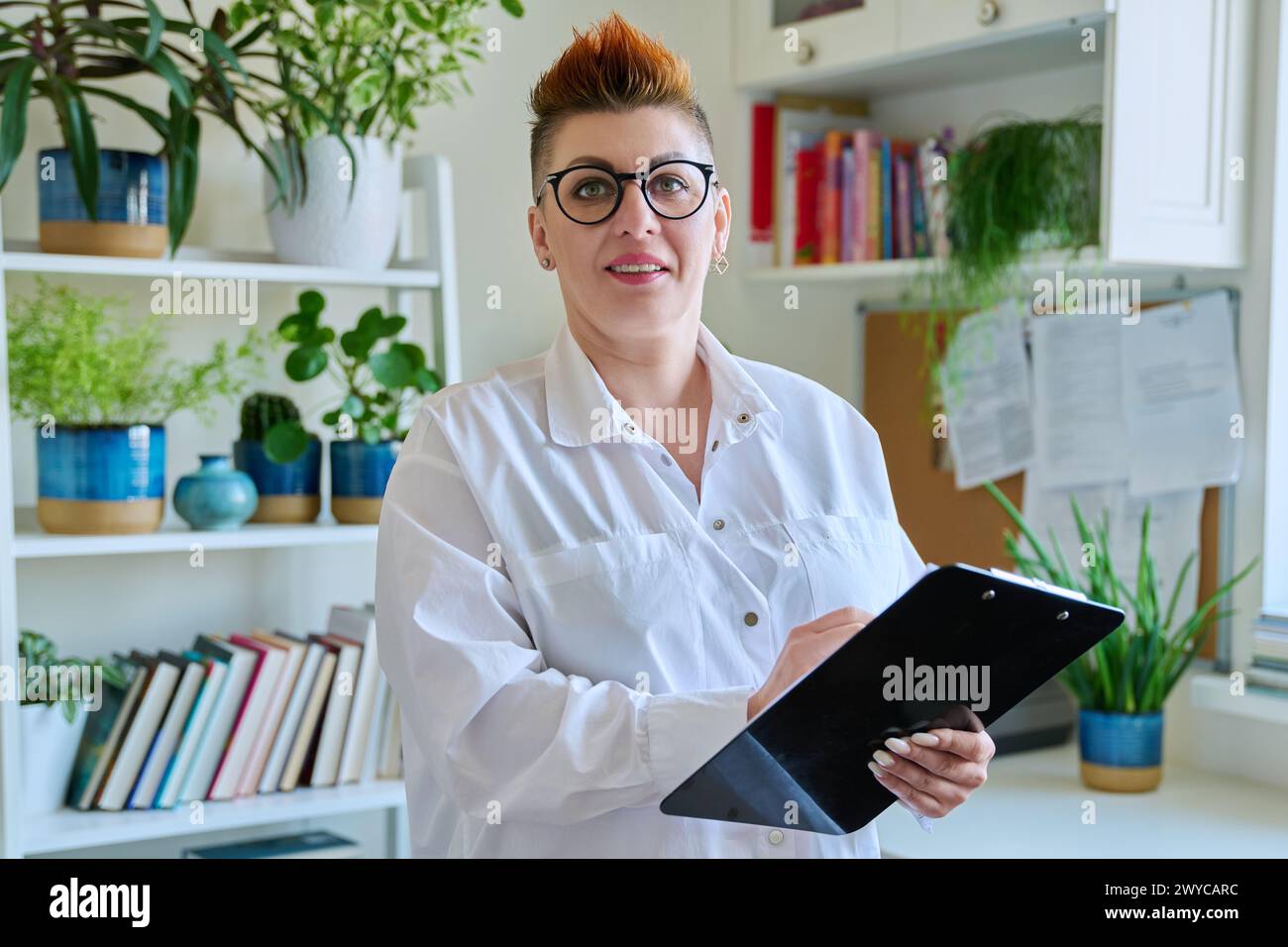 Portrait of smiling middle aged female mental therapist with clipboard ...