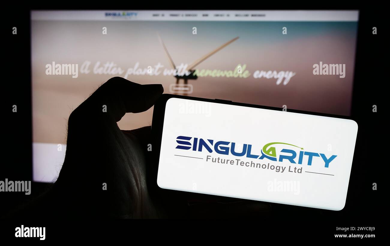 Person holding mobile phone with logo of company Singularity Future Technology Ltd. in front of ...