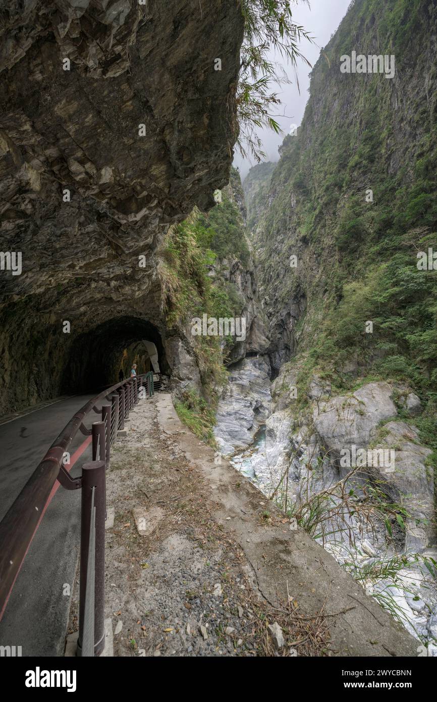 A dramatic view of narrow Taroko gorge with steep cliffs, a flowing ...