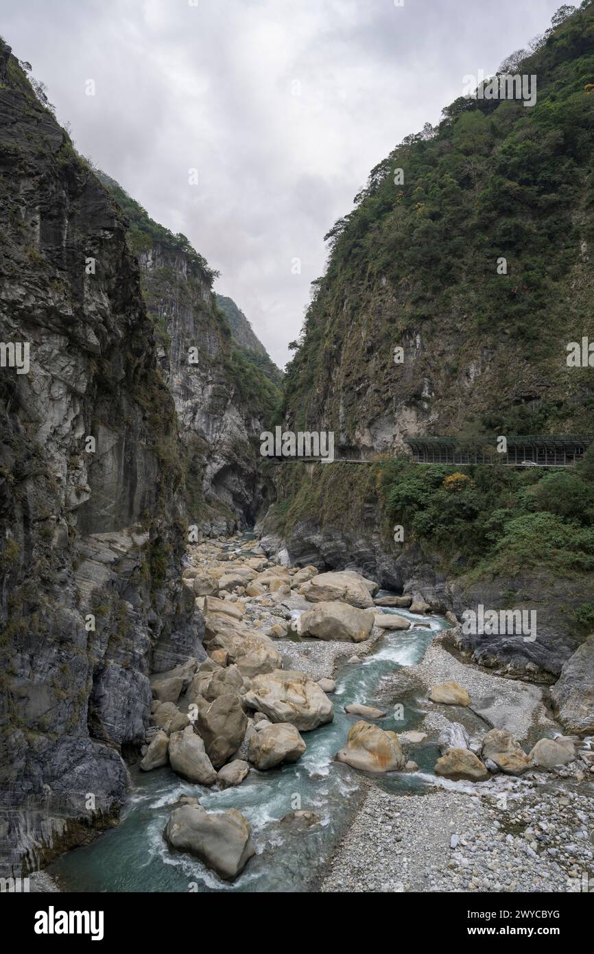 A dramatic view of narrow Taroko gorge with steep cliffs, a flowing ...