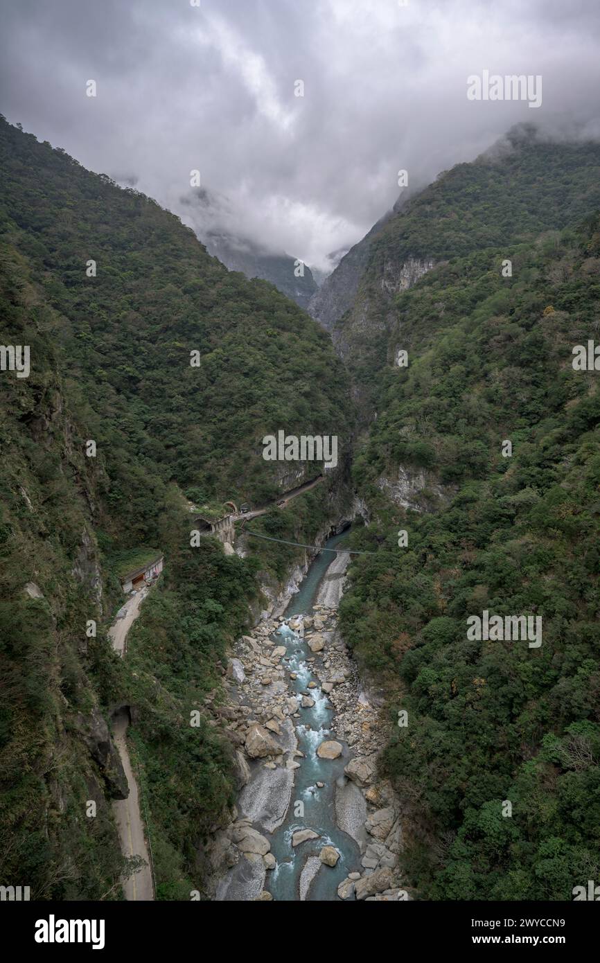 A moody, ethereal view of a misty mountain gorge with a gentle river ...
