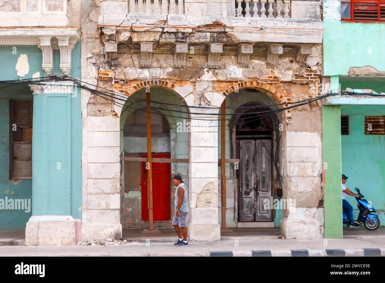 Cuban person walking below a porch in poor condition in Havana, Cuba ...