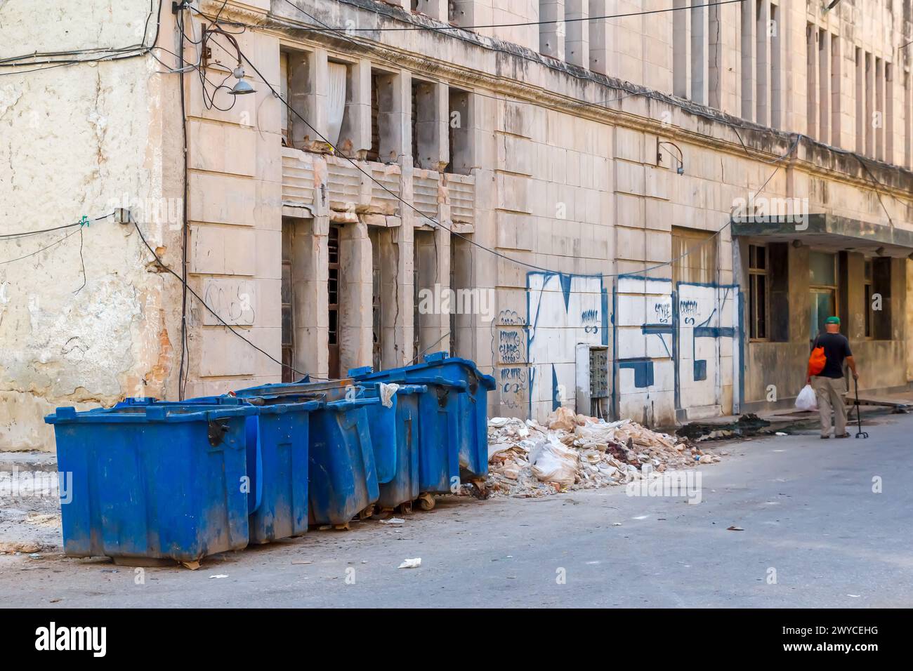 Urban garbage bins and rubble by their side, weathered building facade ...