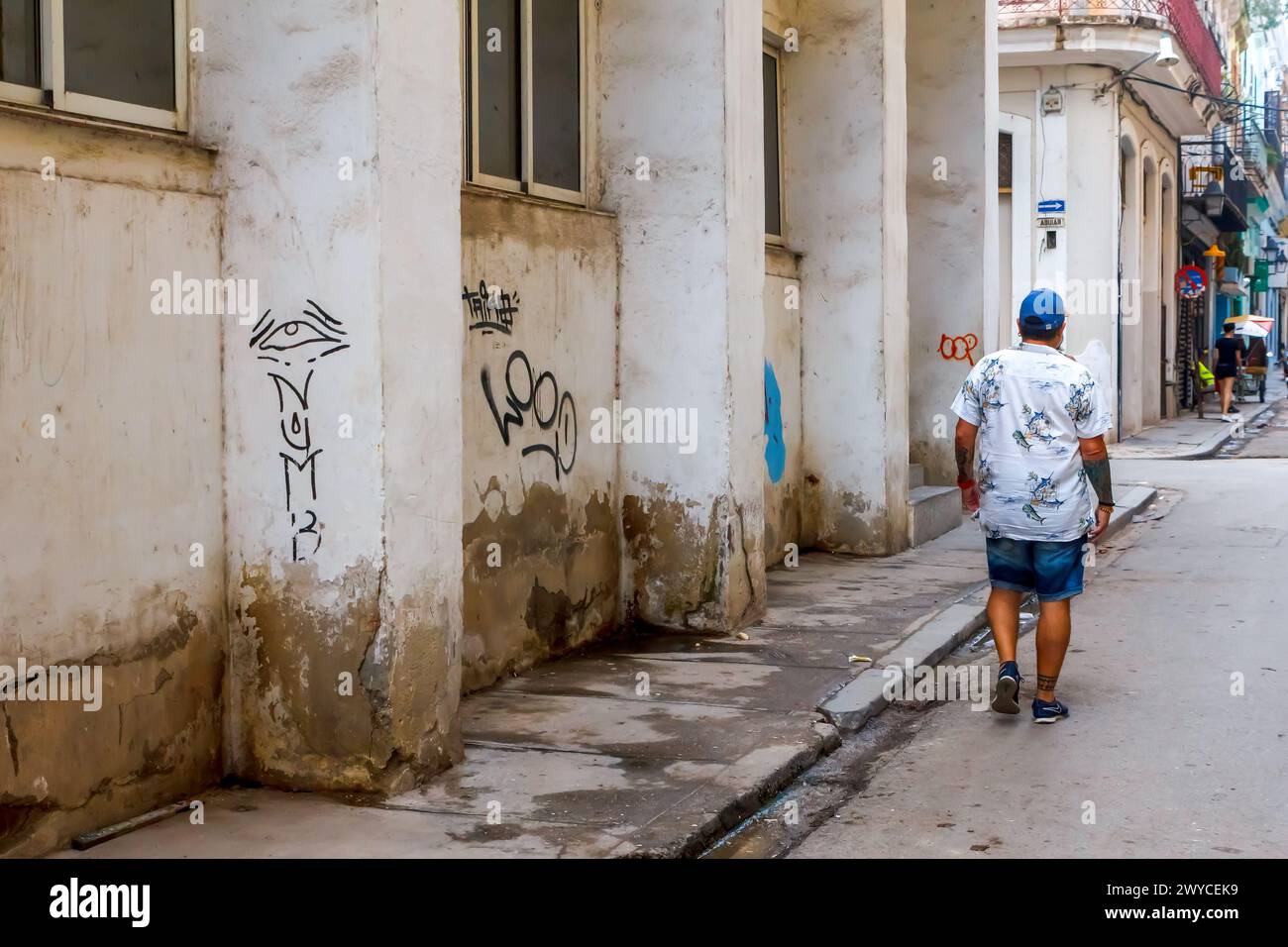 Cuban man walking by dirty wall of building in Havana, Cuba Stock Photo ...