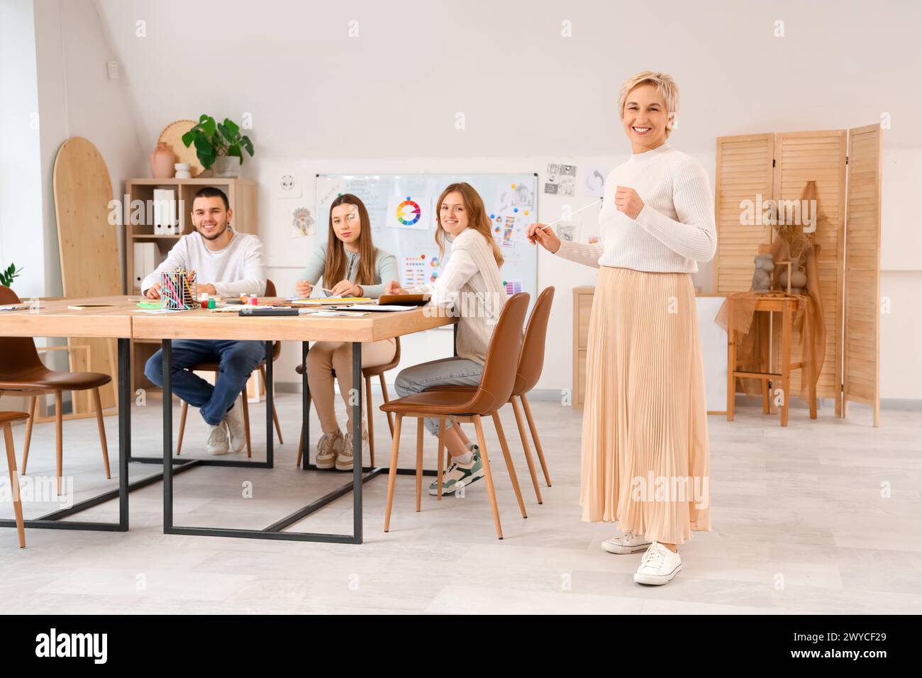 Mature art teacher giving lecture to students at school Stock Photo - Alamy
