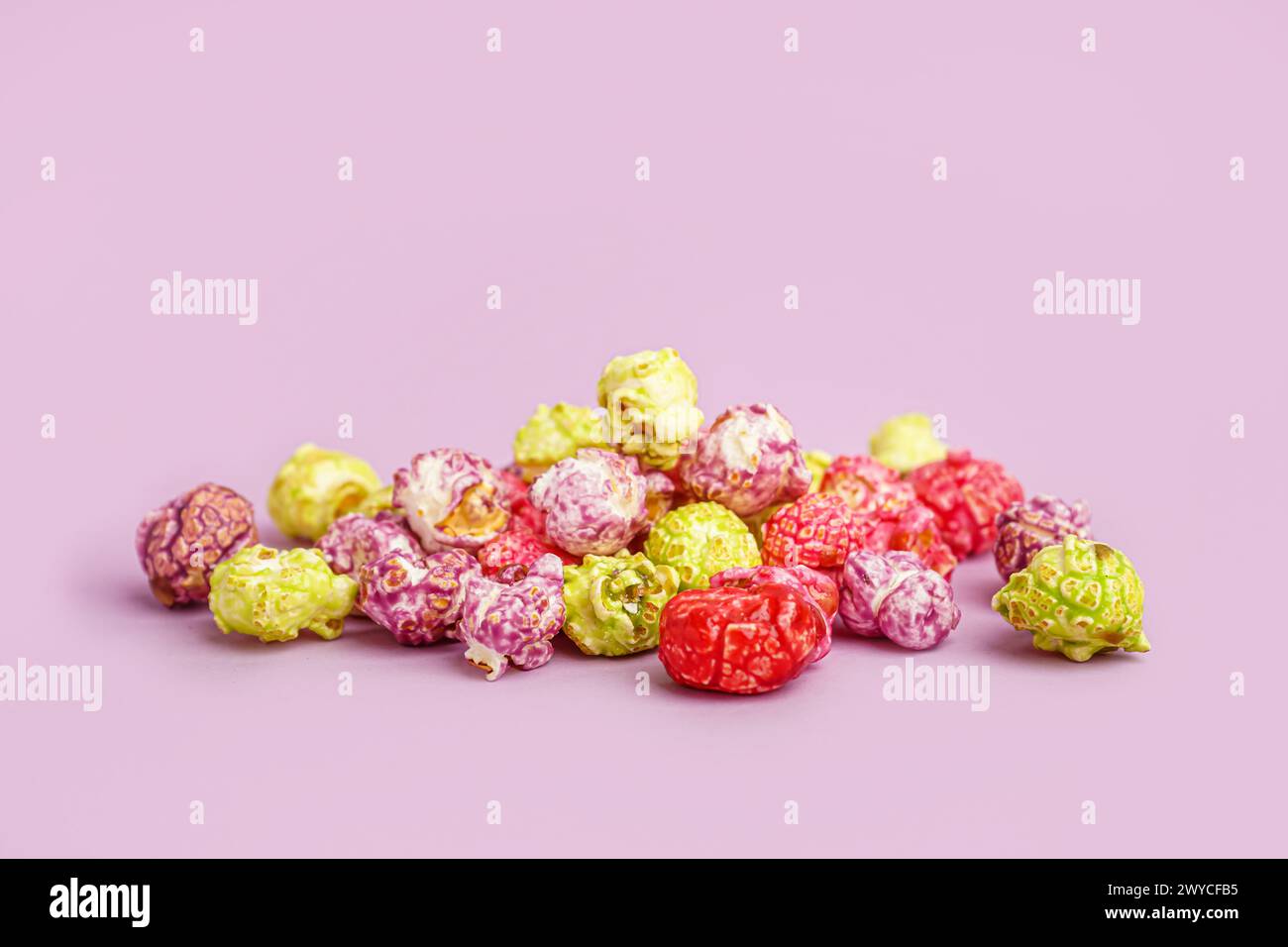 Sweet colorful popcorn on lilac background Stock Photo - Alamy
