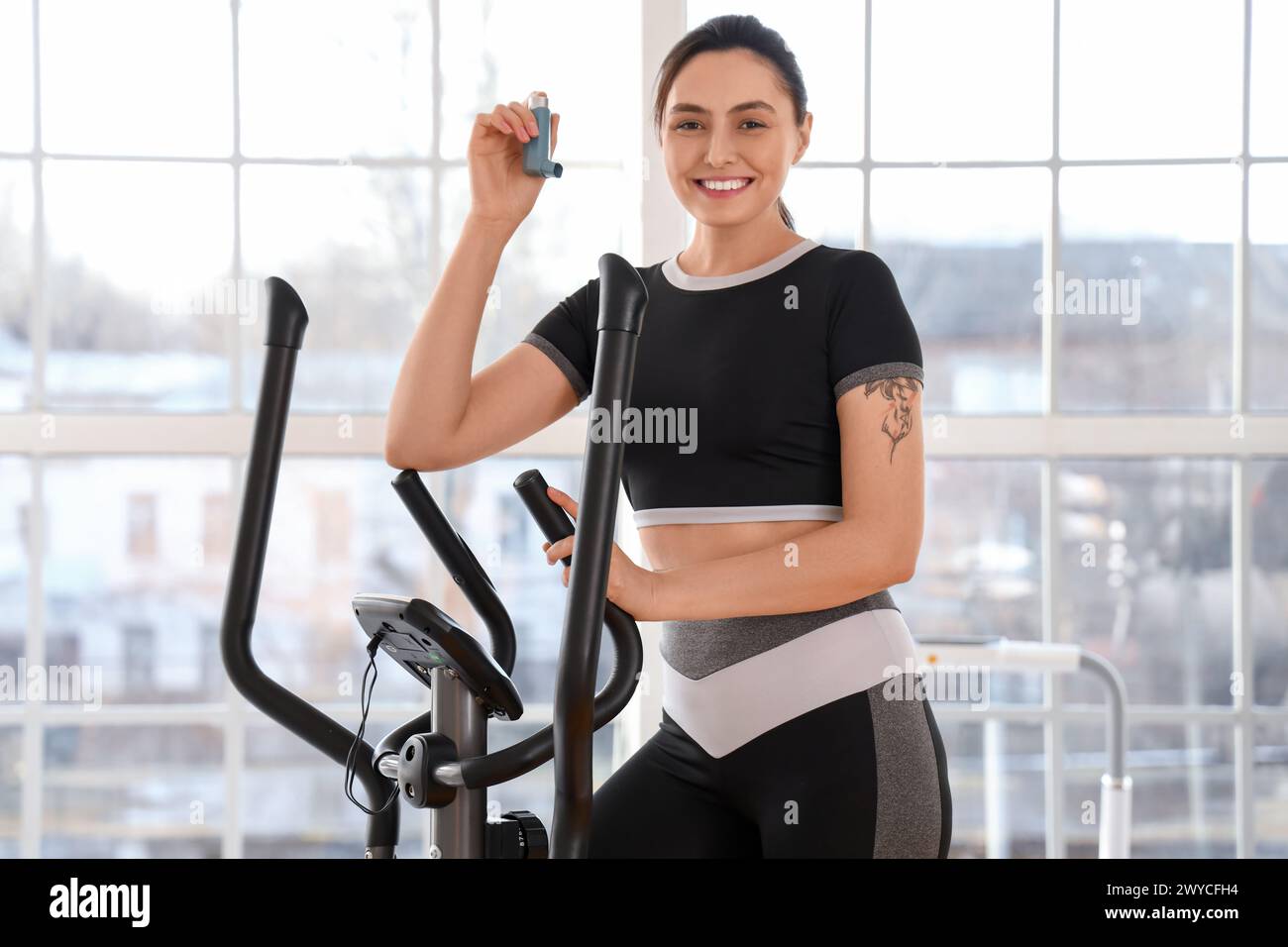 Sporty young woman with inhaler on exercising bike in gym Stock Photo ...