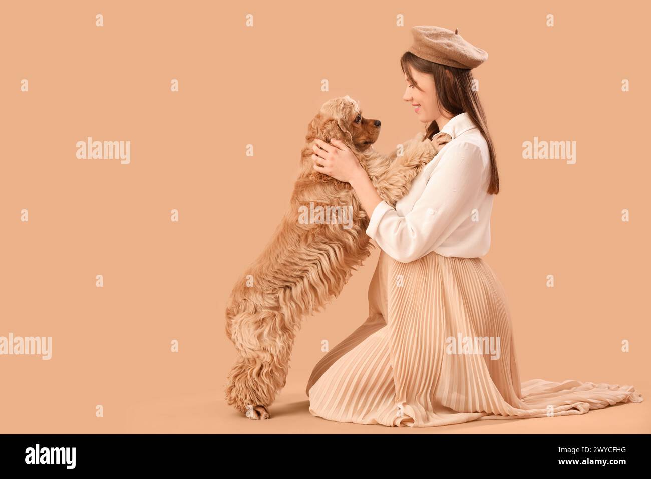 Beautiful pregnant woman with cocker spaniel on beige background Stock ...