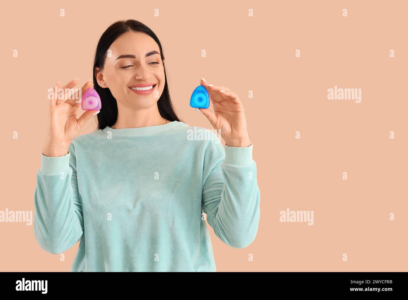 Beautiful young happy woman with different dental floss on beige ...