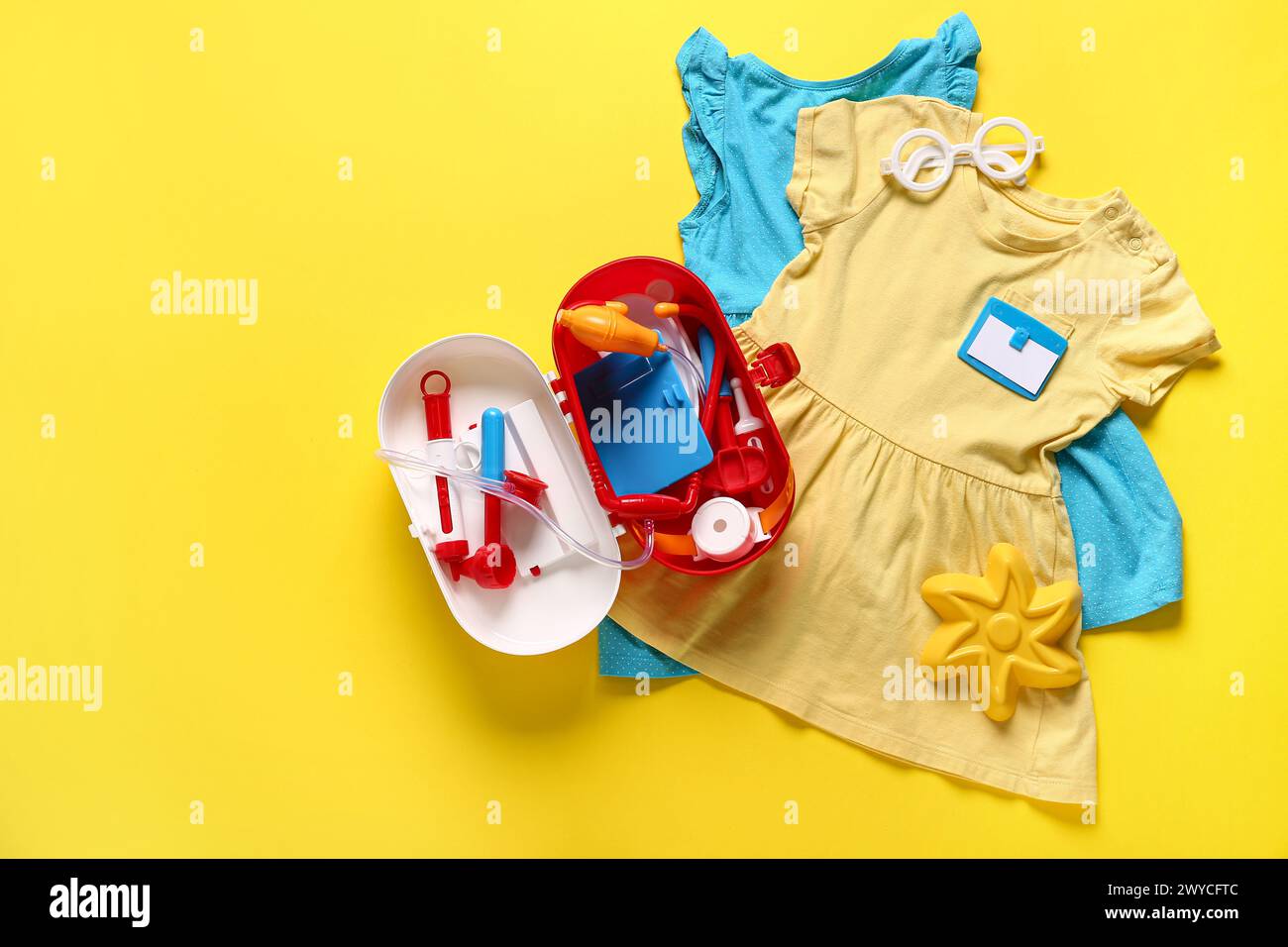 Toy first aid kit with dresses on yellow background. Top view Stock ...