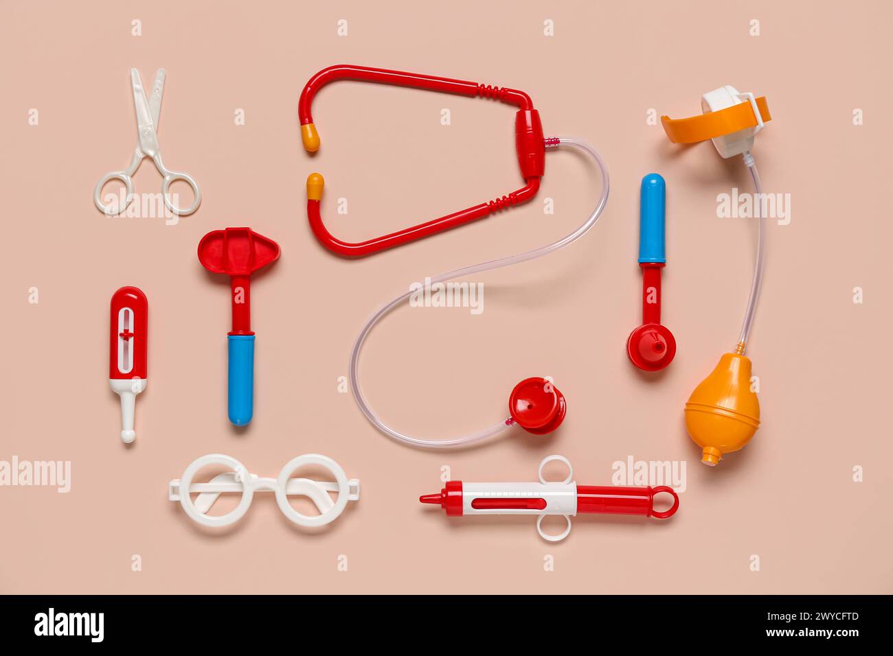 Toy stethoscope with reflex hammer and glasses on beige background. Top ...