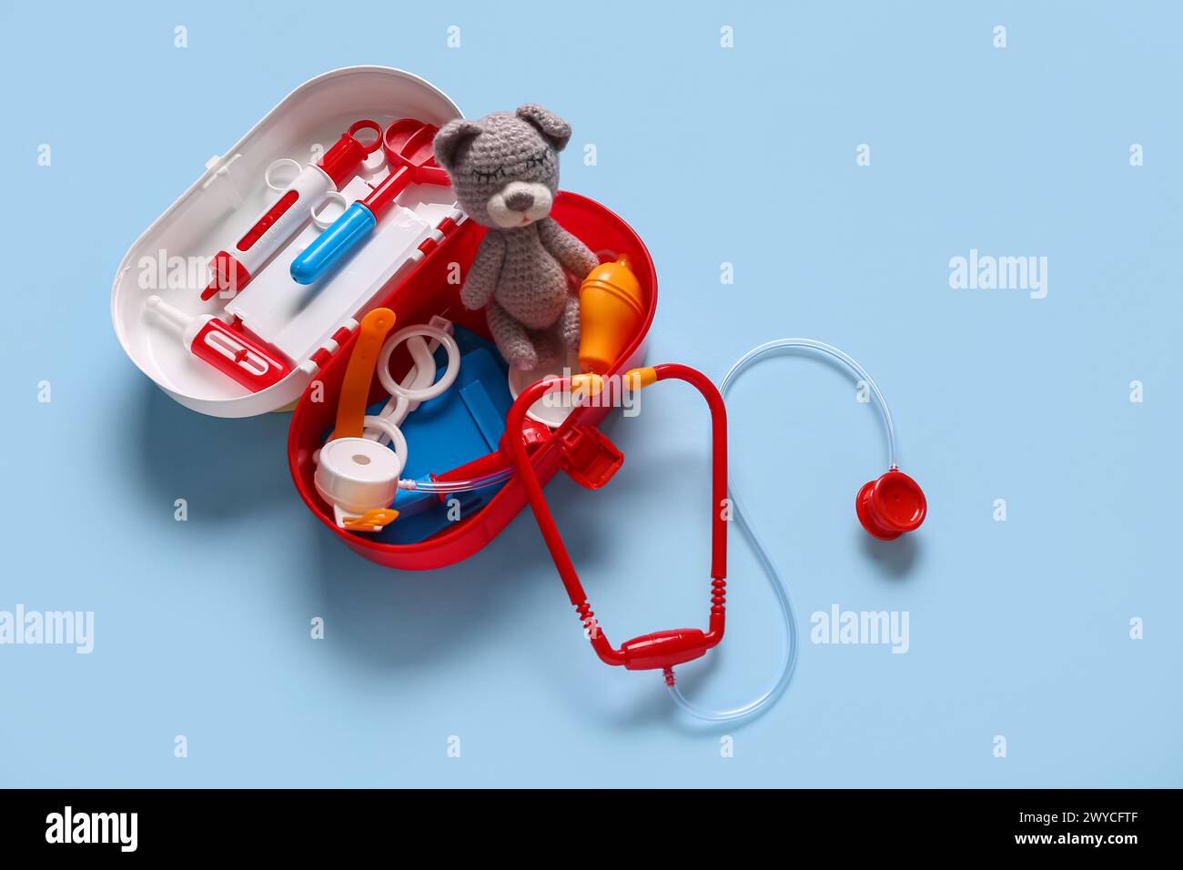 Toy first aid kit with teddy bear and stethoscope on blue background ...