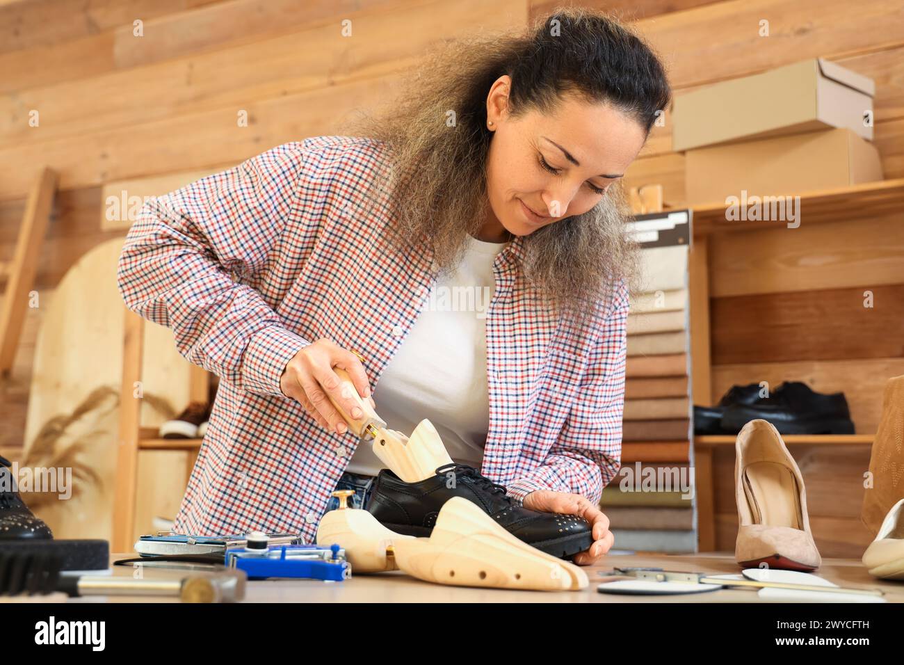 Female shoemaker repairing shoe with tree in workshop Stock Photo - Alamy