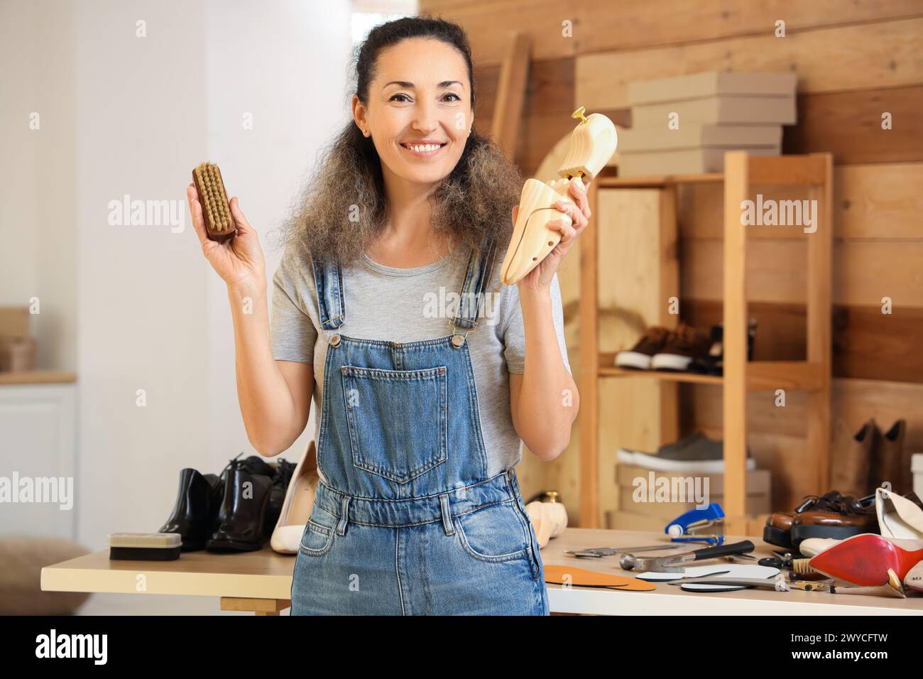 Female shoemaker with brush and wooden shoe tree in workshop Stock ...