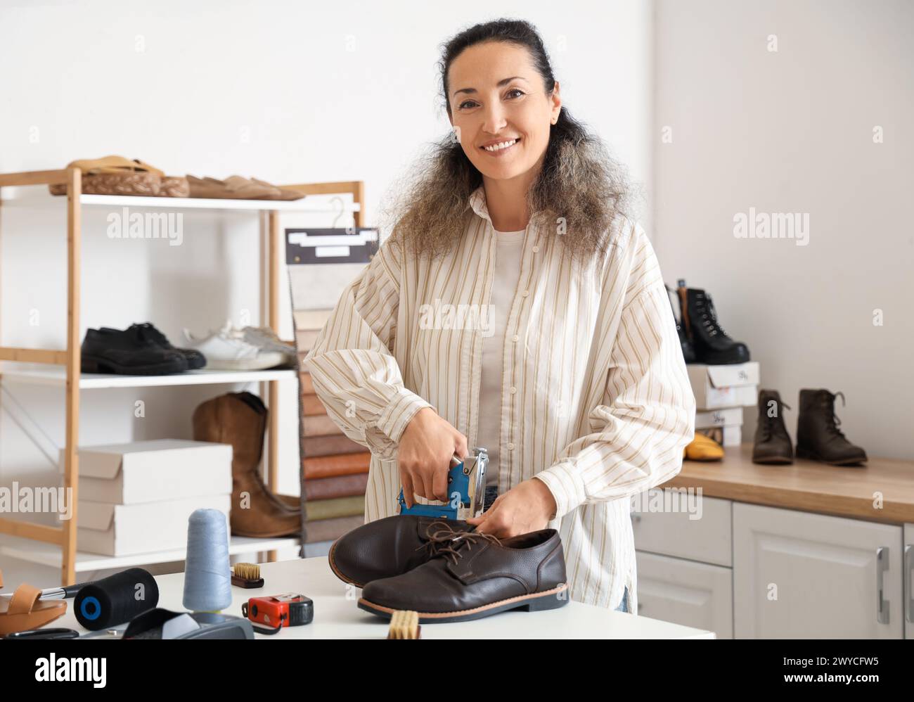 Female shoemaker repairing boot with staple gun in workshop Stock Photo ...