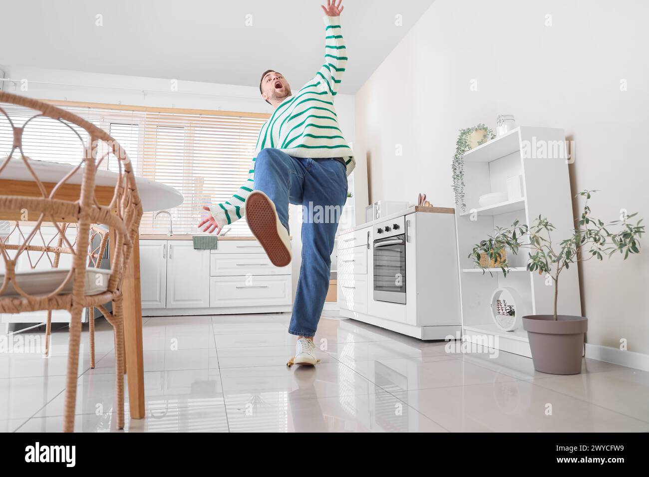 Young man falling after slipping on banana peel in kitchen Stock Photo ...