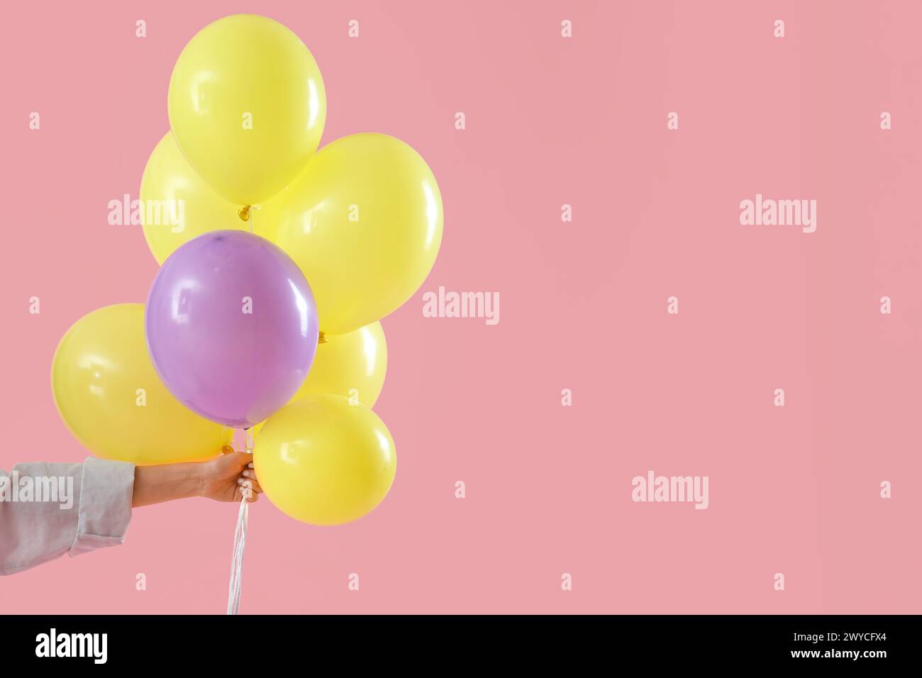 Female hand holding floating balloons on pink background Stock Photo ...