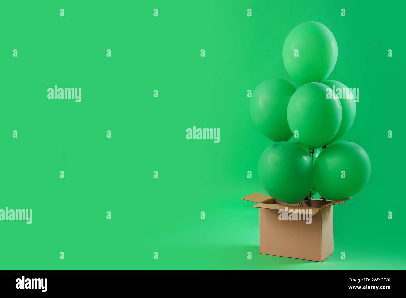 Cardboard box with floating balloons on green background Stock Photo ...