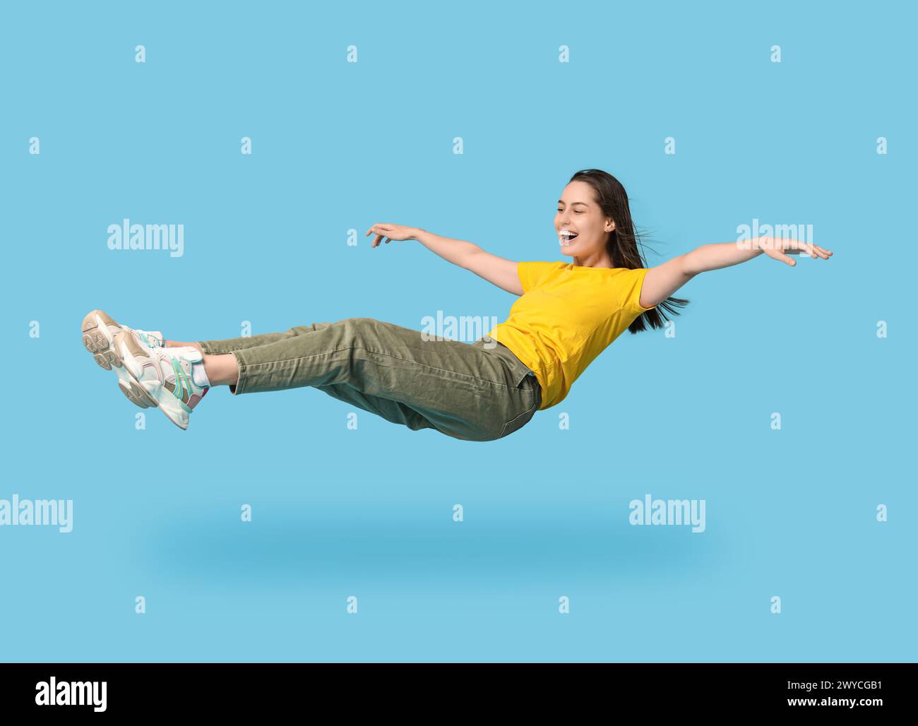 Joyful young woman flying on blue background Stock Photo - Alamy