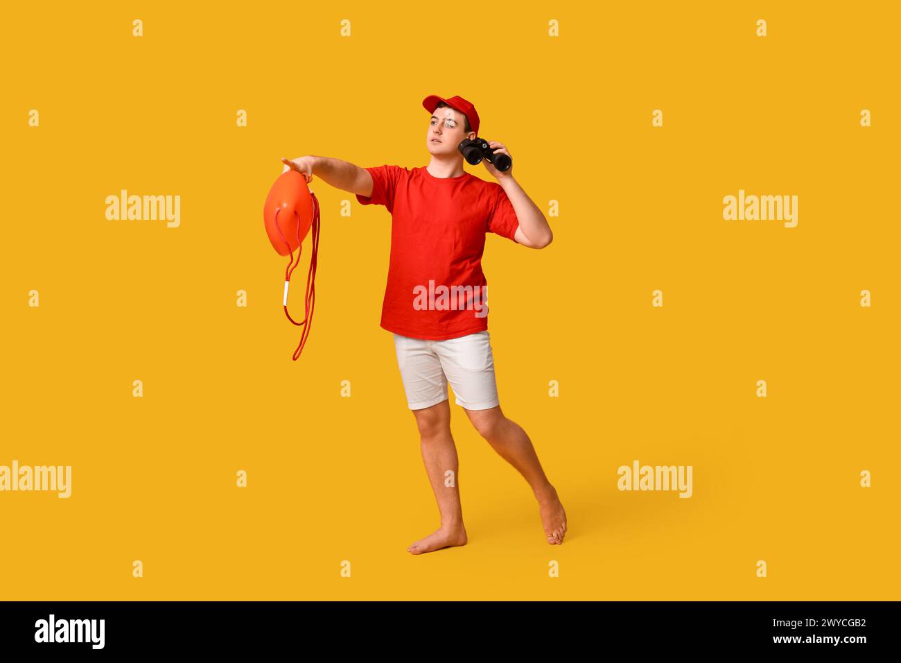 Male lifeguard with rescue tube buoy and binoculars pointing at ...