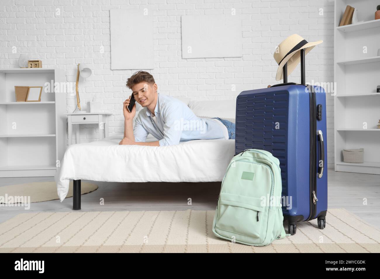 Male tourist talking by mobile phone on bed in hotel room Stock Photo ...