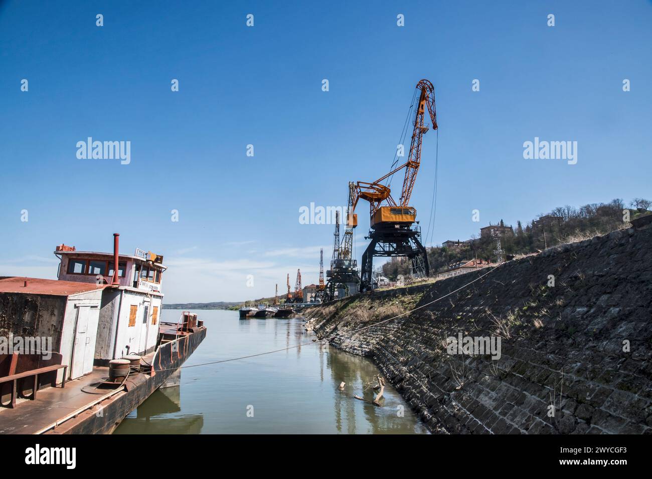 River bulk cargo barge and industrial cranes at river port on sunny day ...