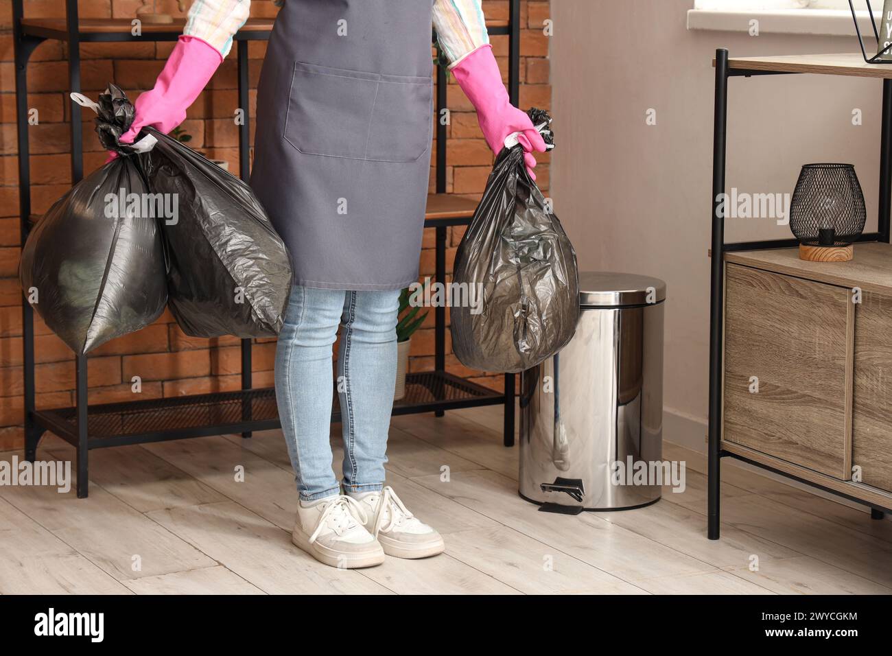 Woman with garbage bags in living room Stock Photo - Alamy
