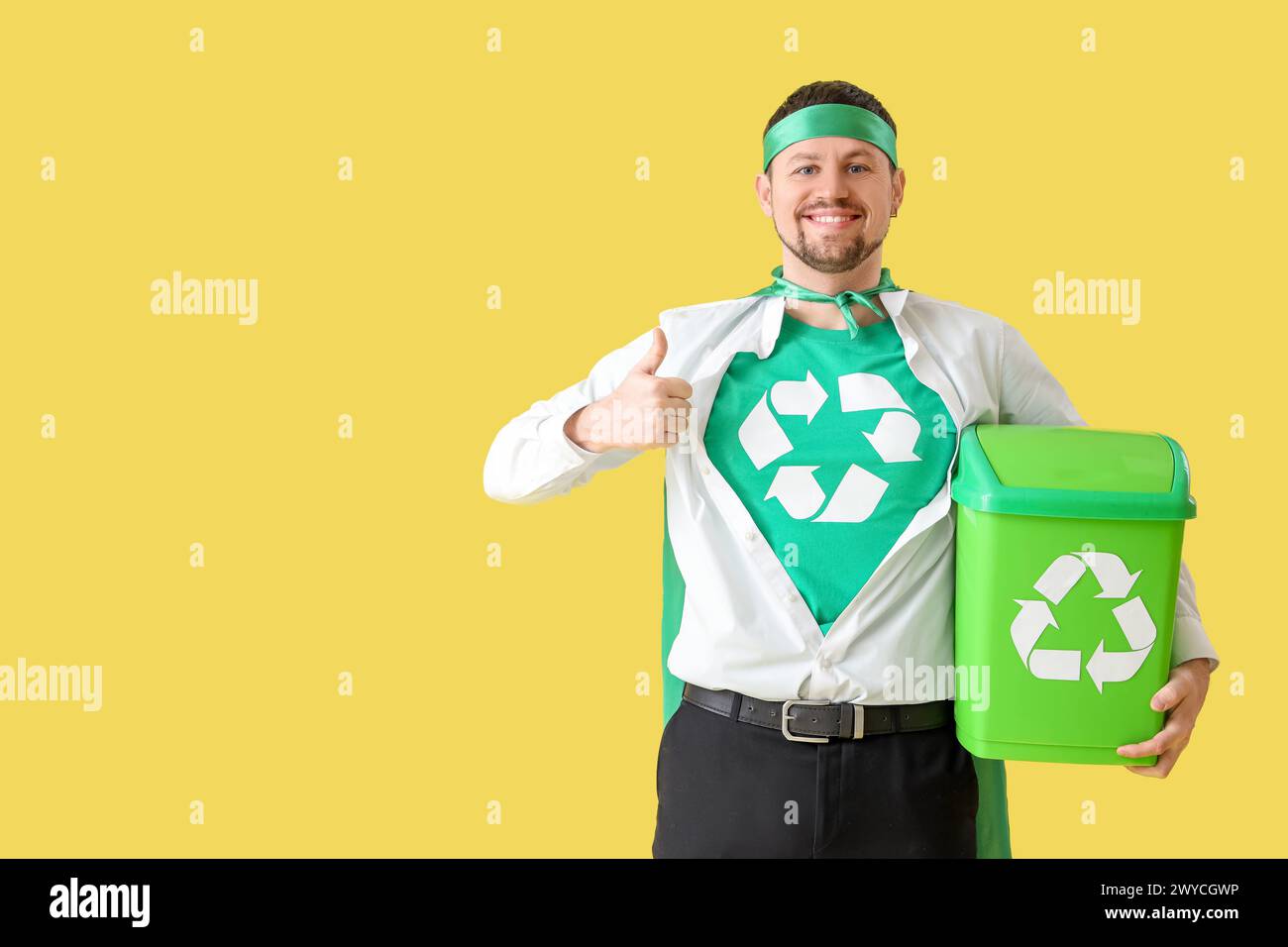 Young man dressed as eco superhero with garbage bin showing thumb-up on ...