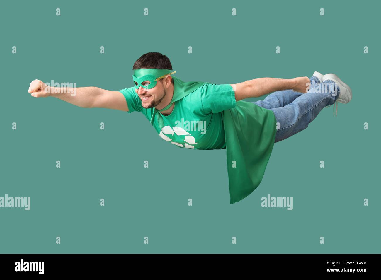 Young man dressed as eco superhero flying on green background. Ecology ...